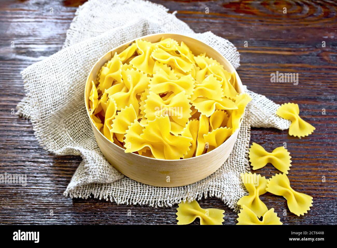 Farfalle pasta in bark box on burlap on the background of dark boards ...