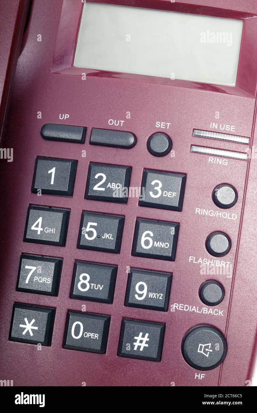 Closeup of dark red office telephone with buttons and empty screen ...