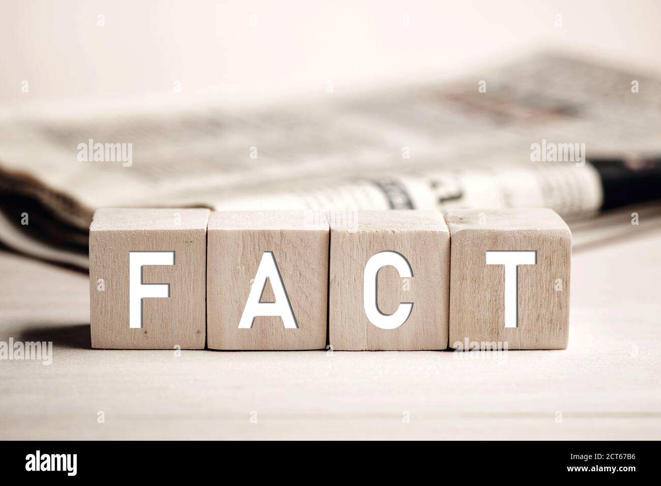The word fact on wooden blocks with a newspaper background. Reliable ...