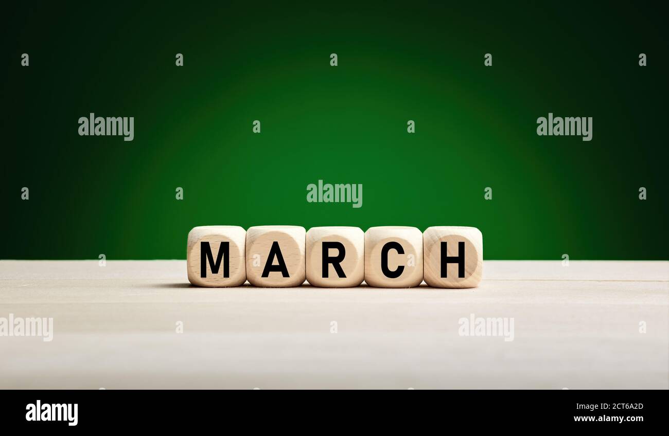 The month March written on wooden cubes with green spring background ...