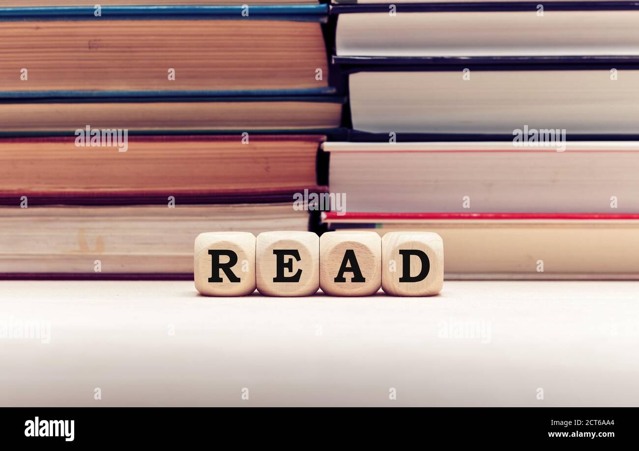 The word read on wooden cubes against stacked books background ...