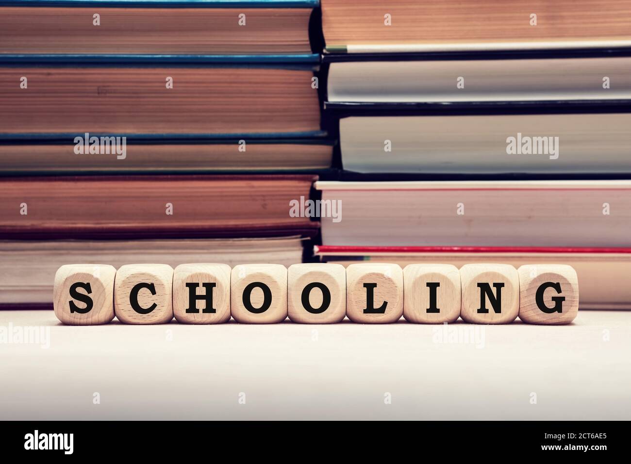 The word schooling on wooden cubes against stacked books background ...