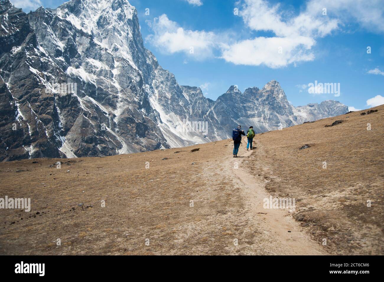 Two climbers on a path facing the steep mountains Stock Photo - Alamy