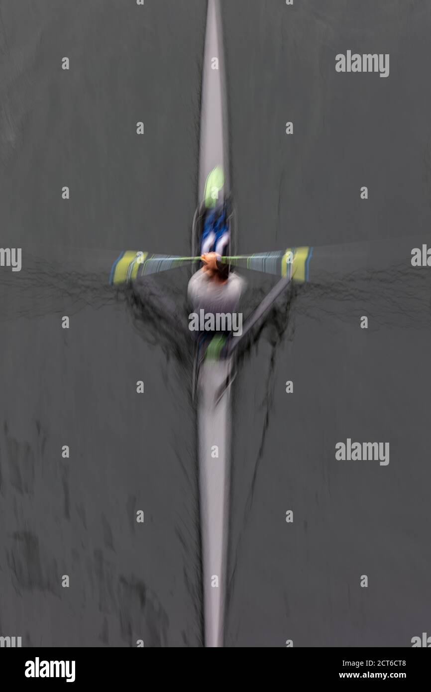 A single scull boat and rower on the water, view from above. Motion ...