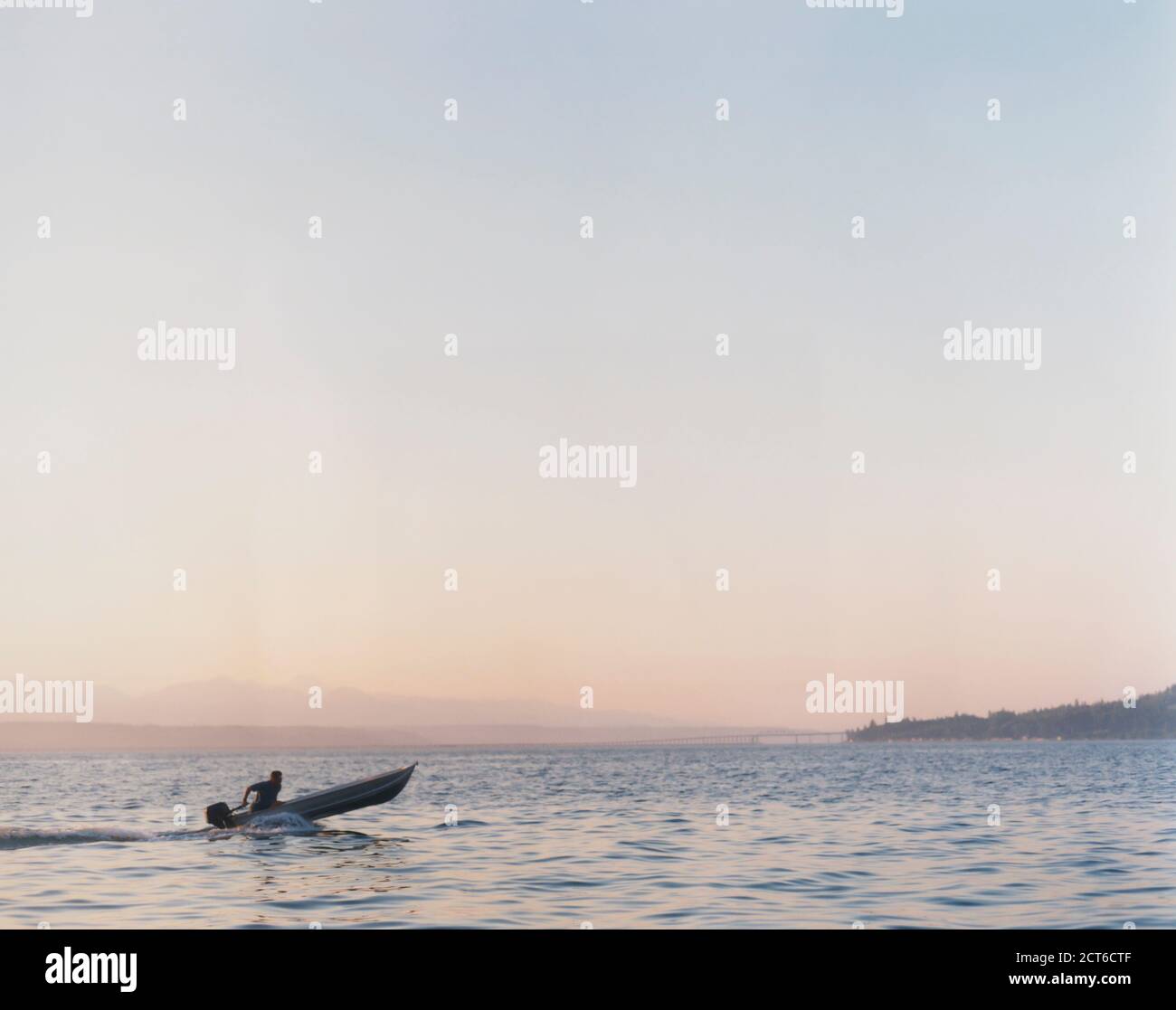 Man riding in small motorized skiff at dusk Stock Photo - Alamy