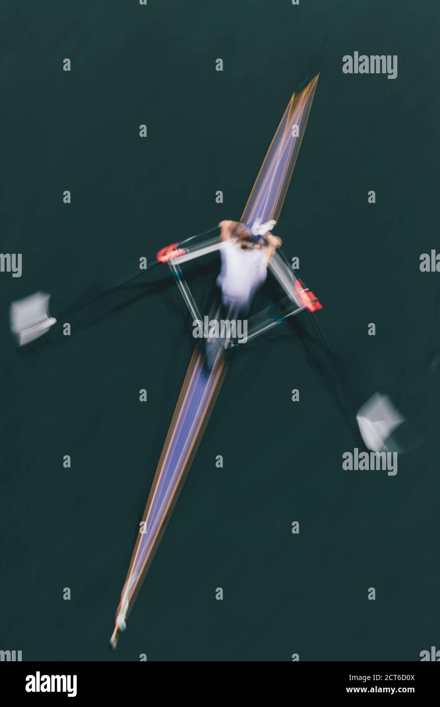 A single scull boat and rower on the water, view from above. Motion ...