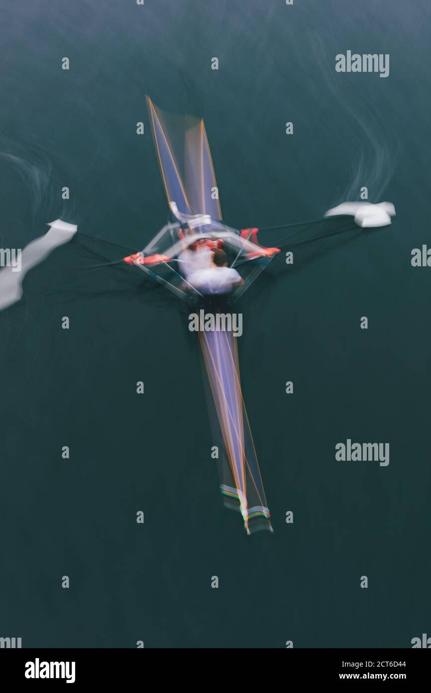 A single scull boat and rower on the water, view from above. Motion ...