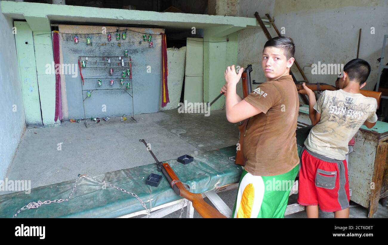 TWO YOUNG BOYS PLAY TARGET SHOOTING IN AN OLD CAROUSEL IN THE STREET ...