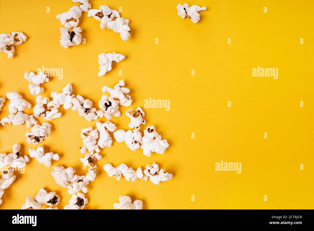 Popcorn scattered on yellow background Stock Photo - Alamy