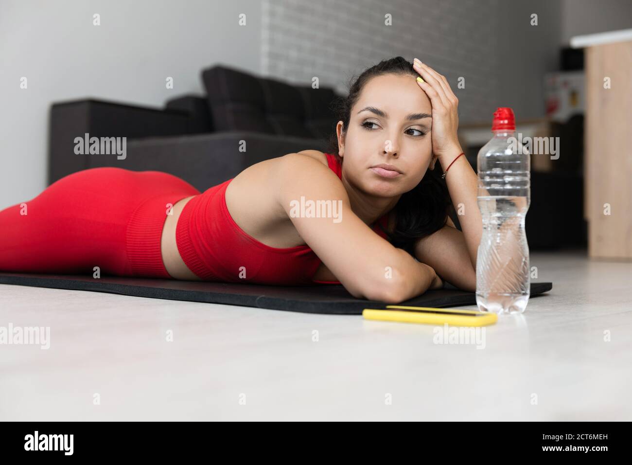 Young woman in red tracksuit doing exercise or yoga at home. Tired ...
