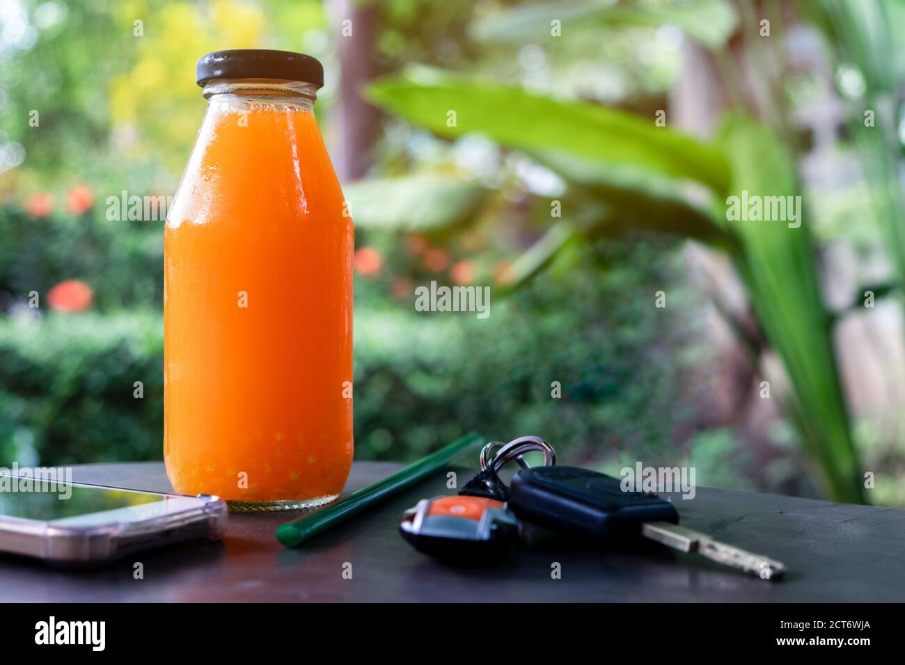 Freshly squeezed orange juice in a bottle with smart phone and keys ...