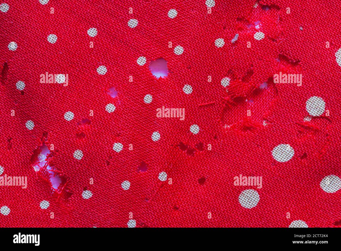 Moth holes in red with white polka dots fabric Stock Photo - Alamy