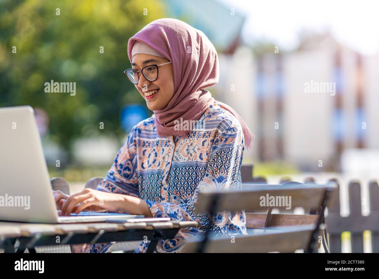 Young Muslim woman using a laptop in outdoor cafe Stock Photo - Alamy