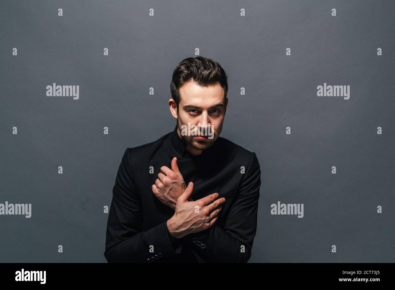 Close up portrait of a young handsome man in a suit, hands on the chest ...