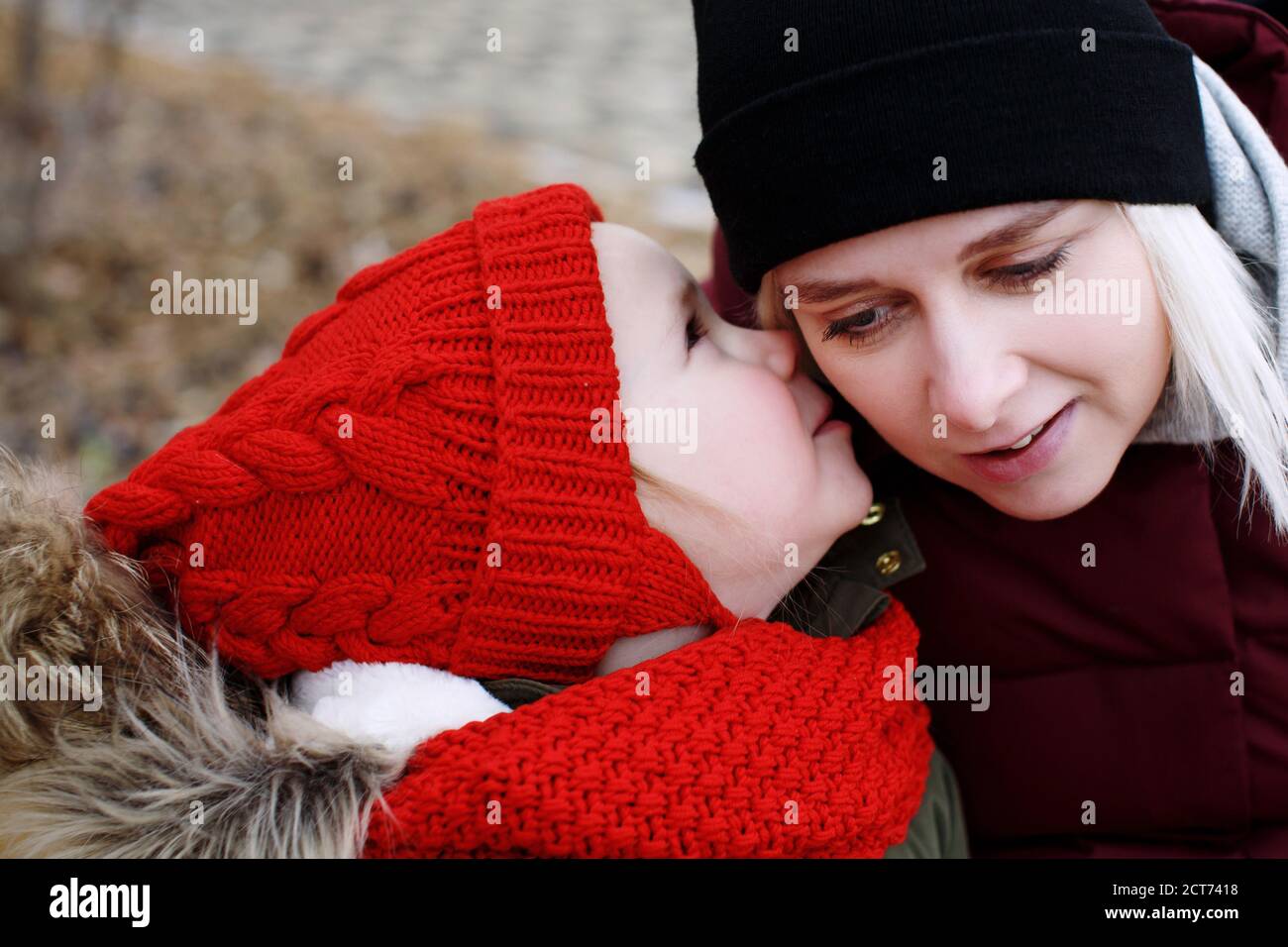 Cute little preschool daughter whispering a secret to young beautiful ...