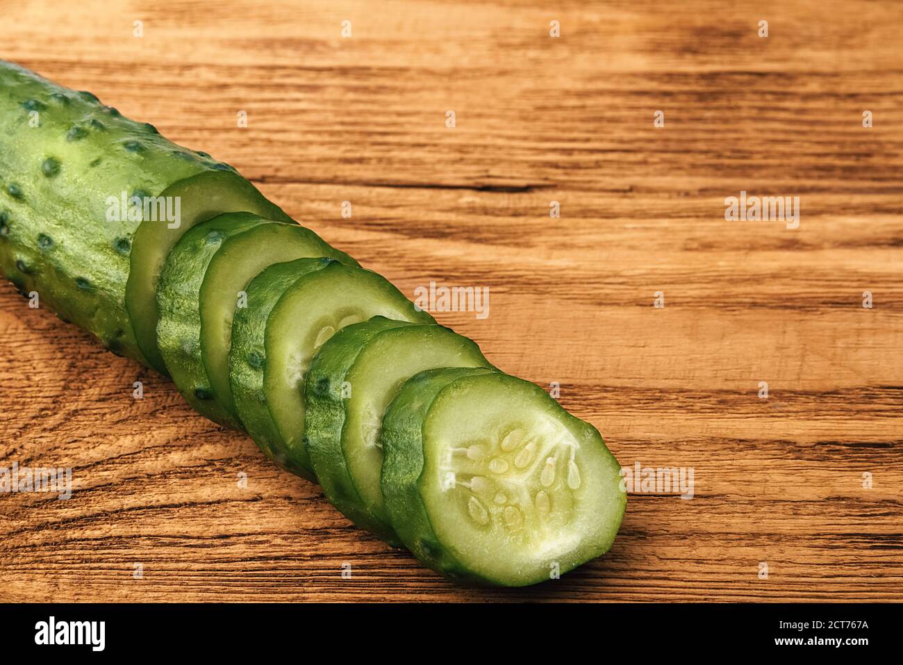 Cucumber sliced lies on a wooden table. Next to the place for the ...