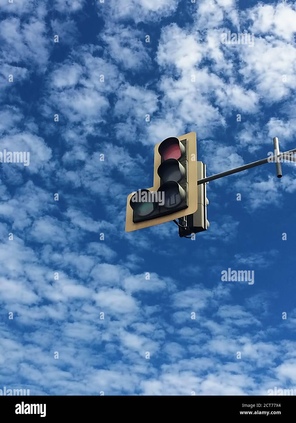 Traffic lights against a blue sky and lots of white clouds. The red ...
