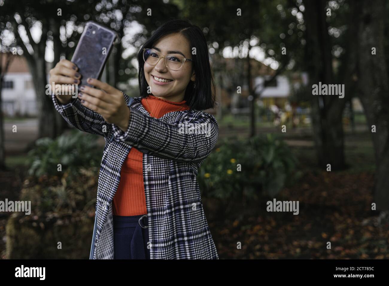 Woman smiling and taking a selfie with her phone Stock Photo - Alamy