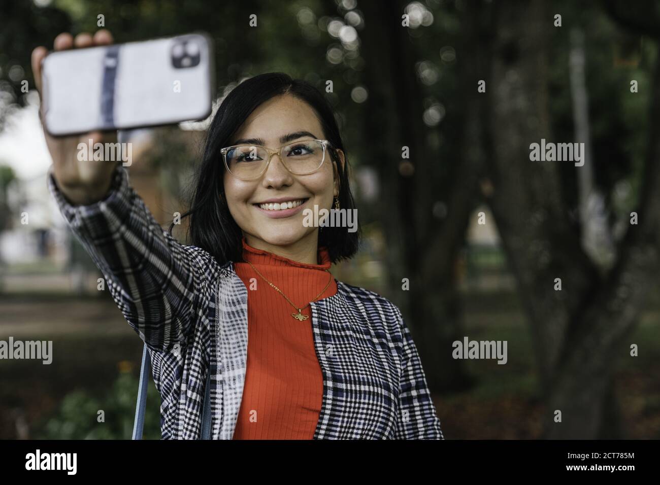 Woman smiling and taking a selfie with her phone Stock Photo - Alamy