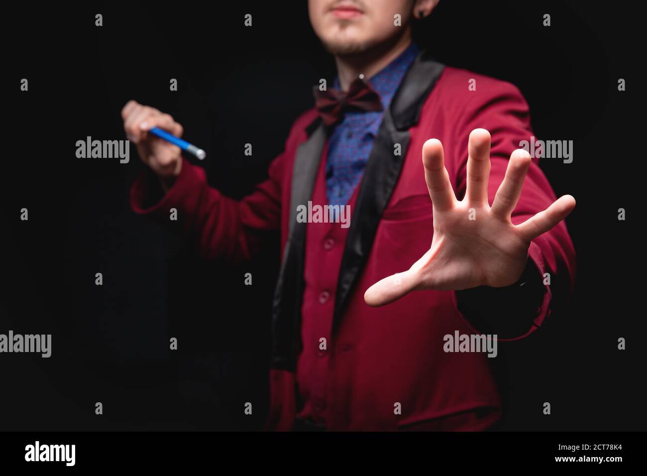 Magician man with magic wand on black background Stock Photo - Alamy