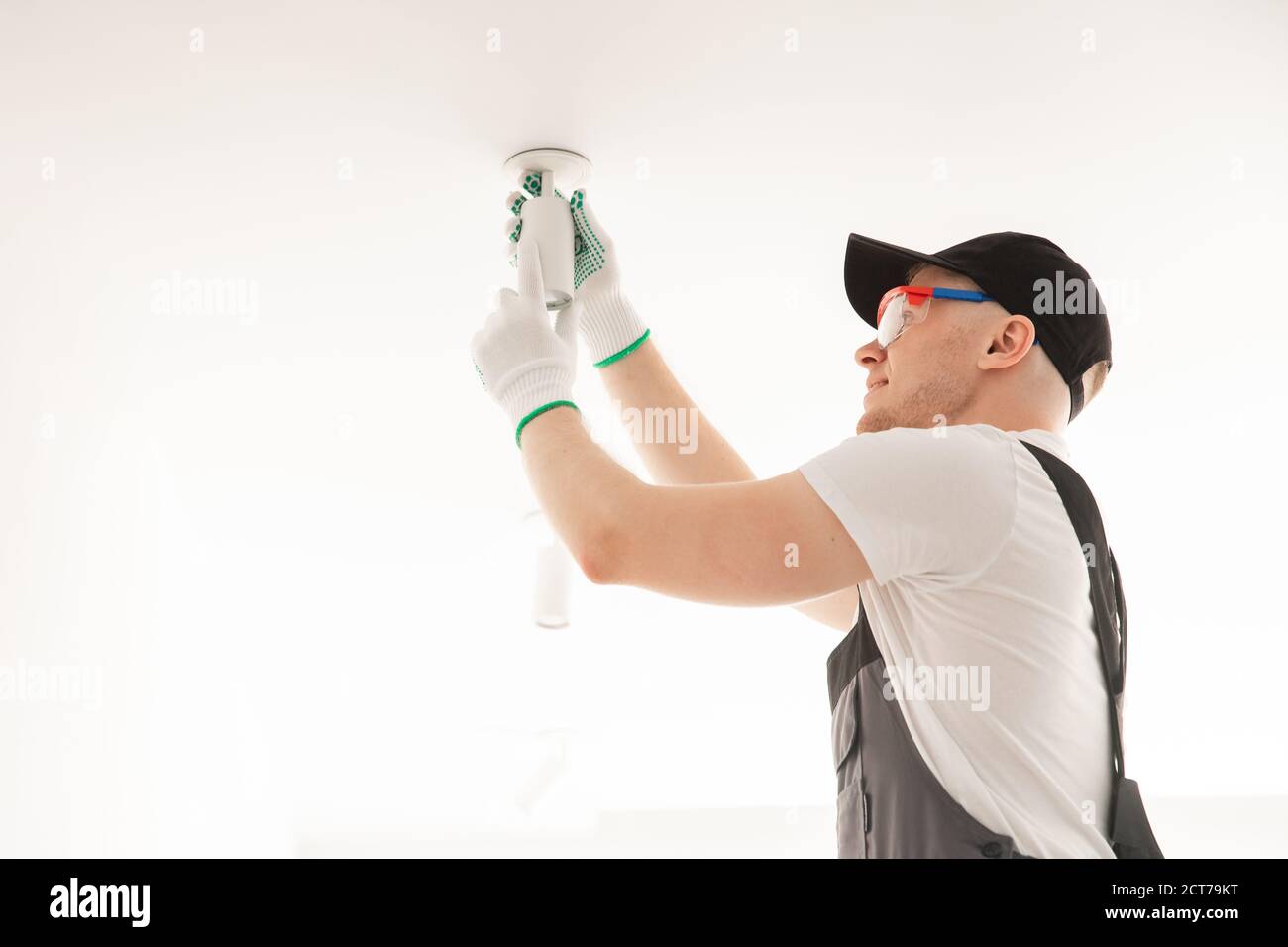 Electrician worker man assembling electric lamps in new apartment Stock ...