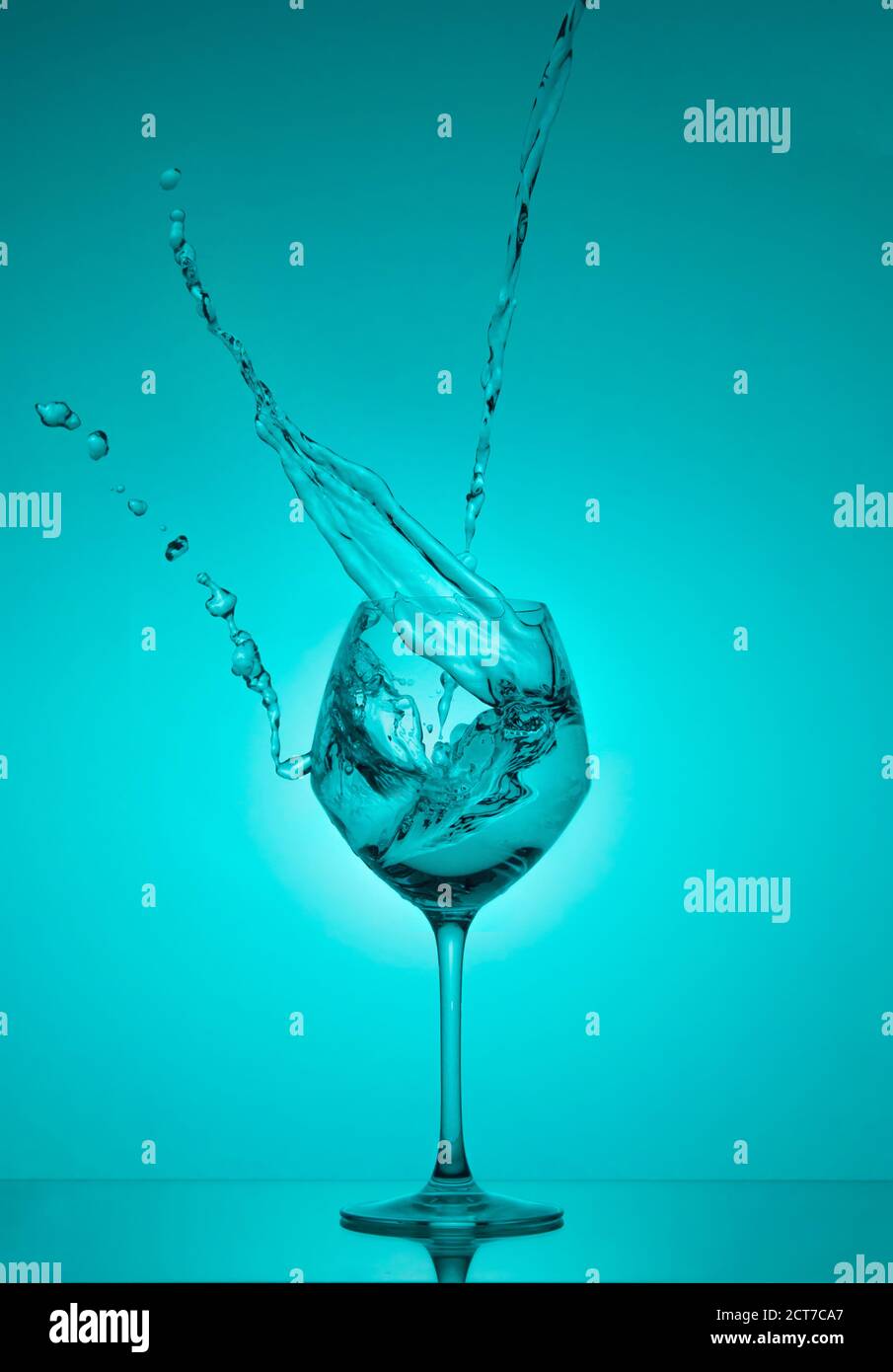 Water splash in out of glass. Water splashing out of a tall wine glass ...