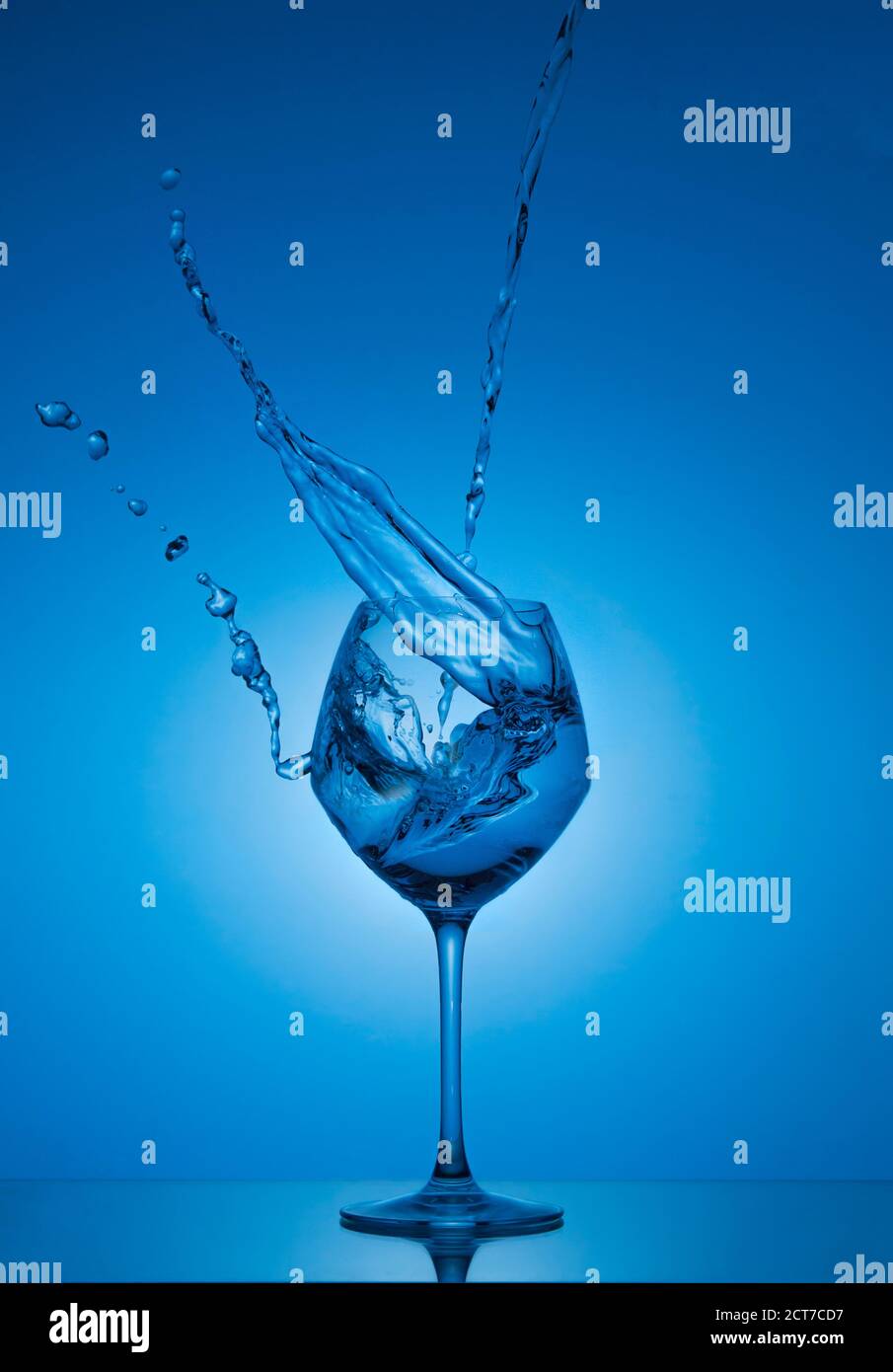Water splash in out of glass. Water splashing out of a tall wine glass ...