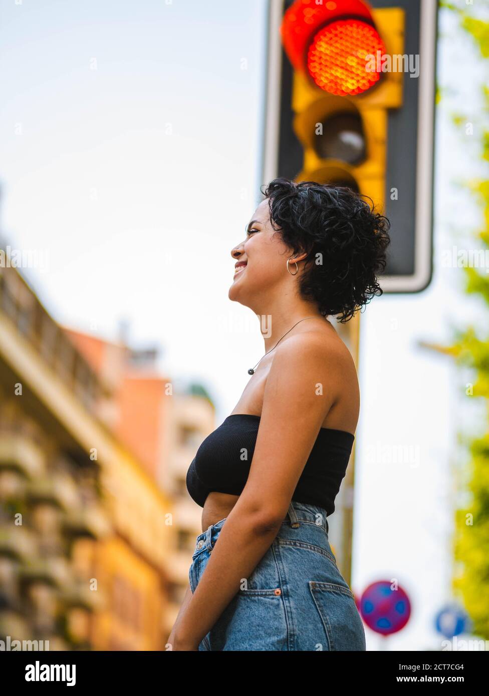 Vertical shot of a Brazilian female with a traffic light in the back ...