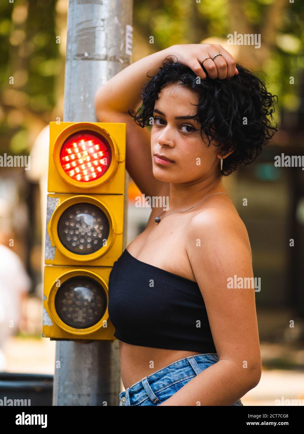 Vertical shot of a Brazilian female with a traffic light in the back ...