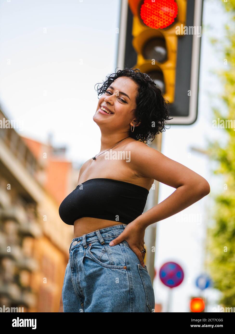 Vertical shot of a Brazilian female with a traffic light in the back ...
