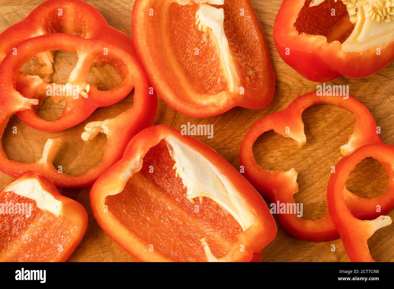 Sliced pieces, parts, lobes of sweet pepper, red, on a wooden board ...