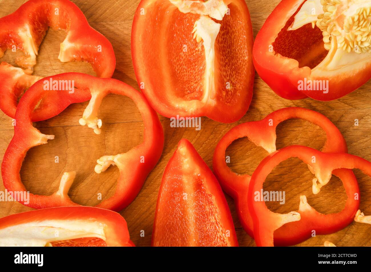 Sliced pieces, parts, lobes of sweet pepper, red, on a wooden board ...