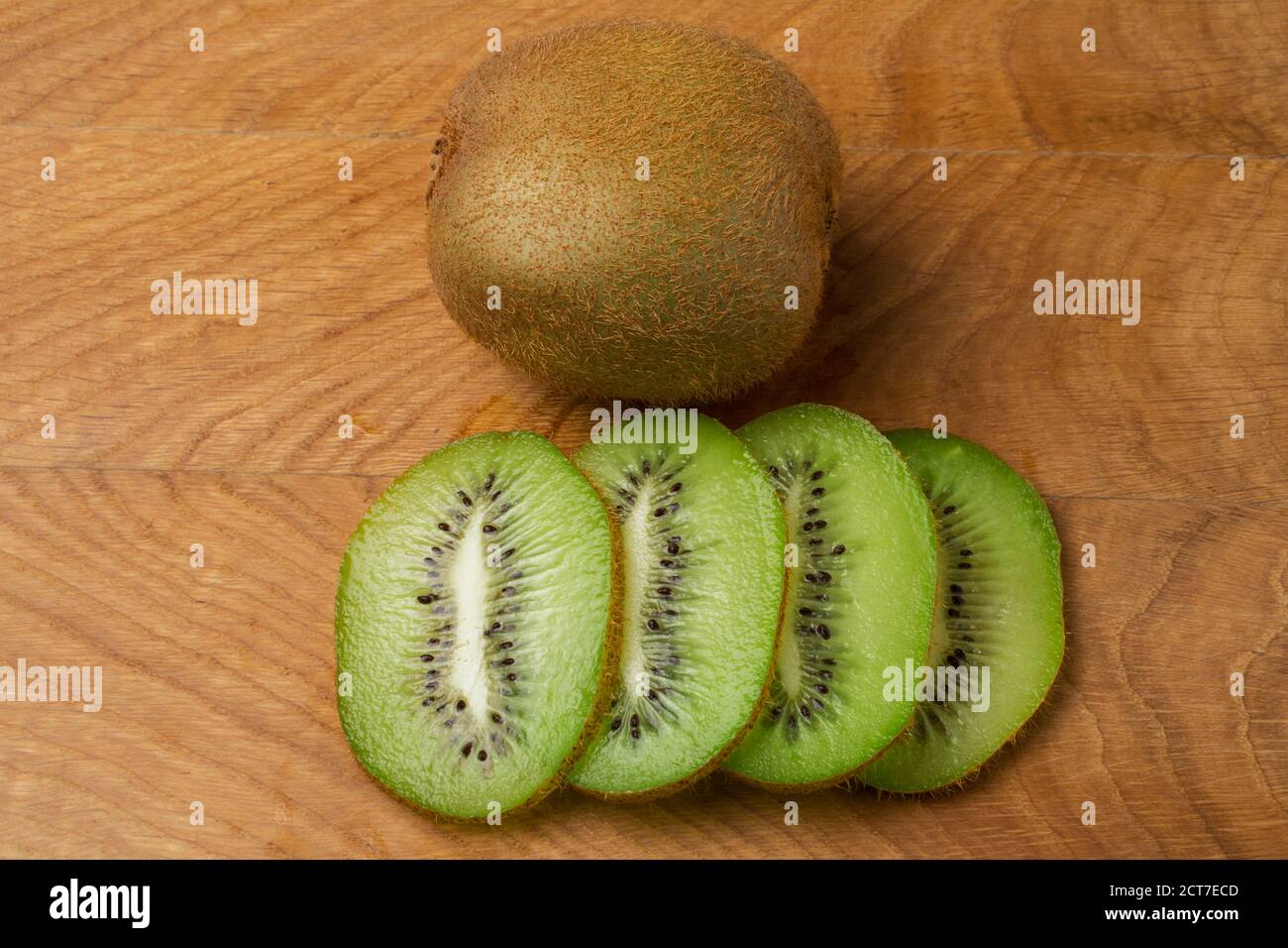 Kiwi single whole and sliced in pieces on a wooden board Stock Photo ...
