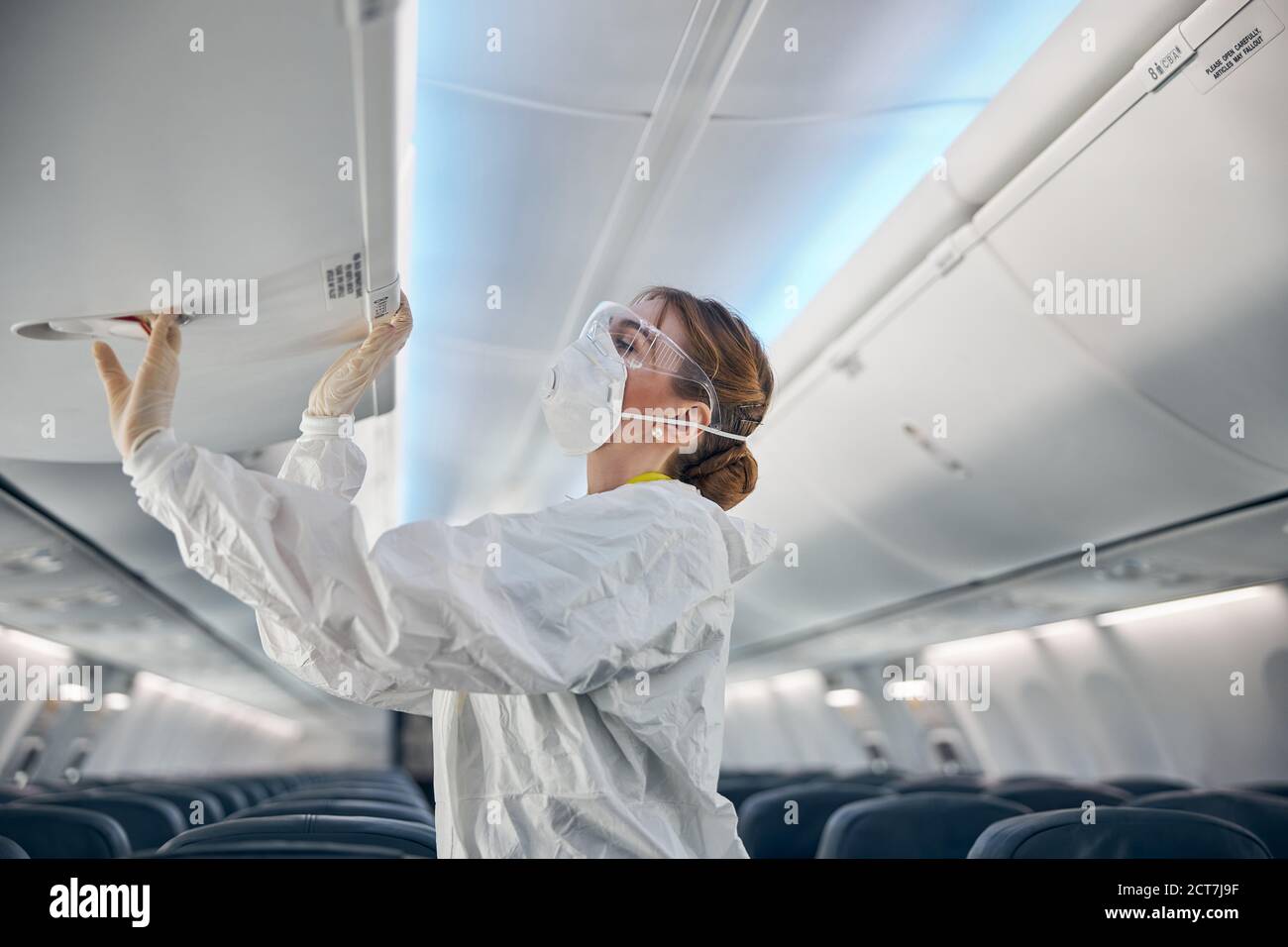 Female air hostess in white uniform closing cabin compartment Stock ...