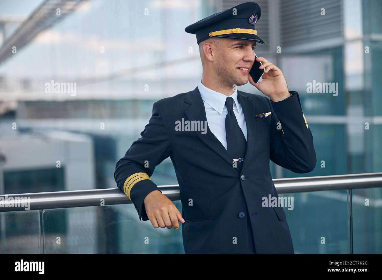 Cheerful male pilot talking on cellphone at airport Stock Photo - Alamy