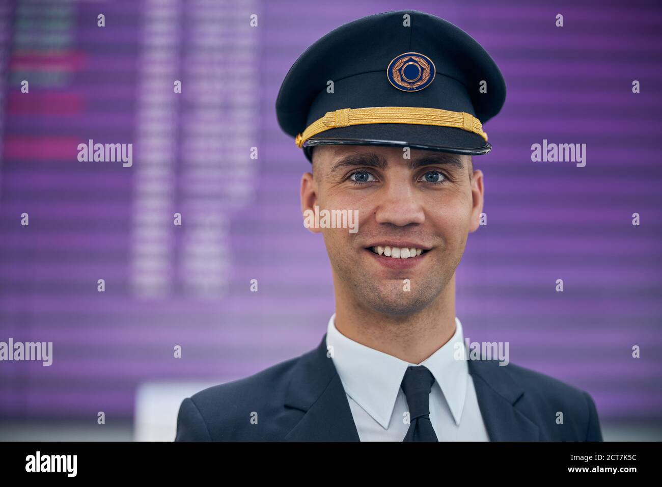 Cheerful male pilot standing in airport terminal Stock Photo - Alamy