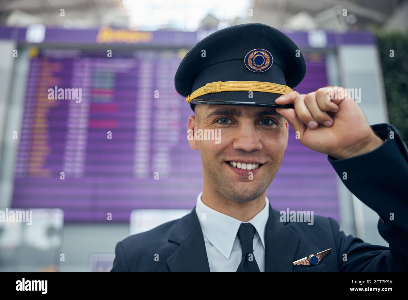 Joyful male pilot standing in airport terminal Stock Photo - Alamy