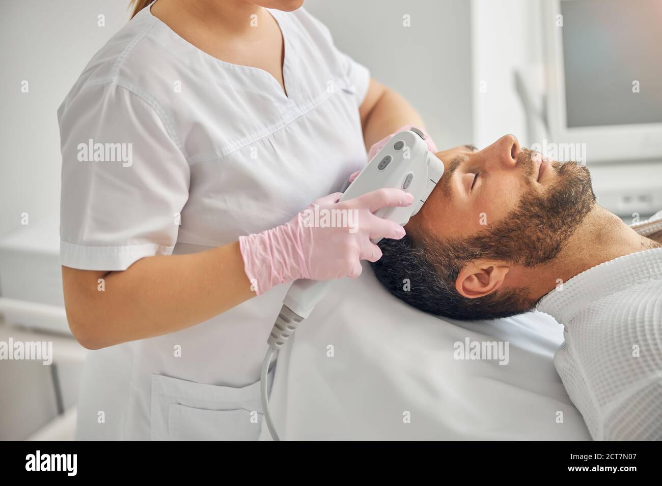 Handsome young man receiving laser facial treatment Stock Photo - Alamy