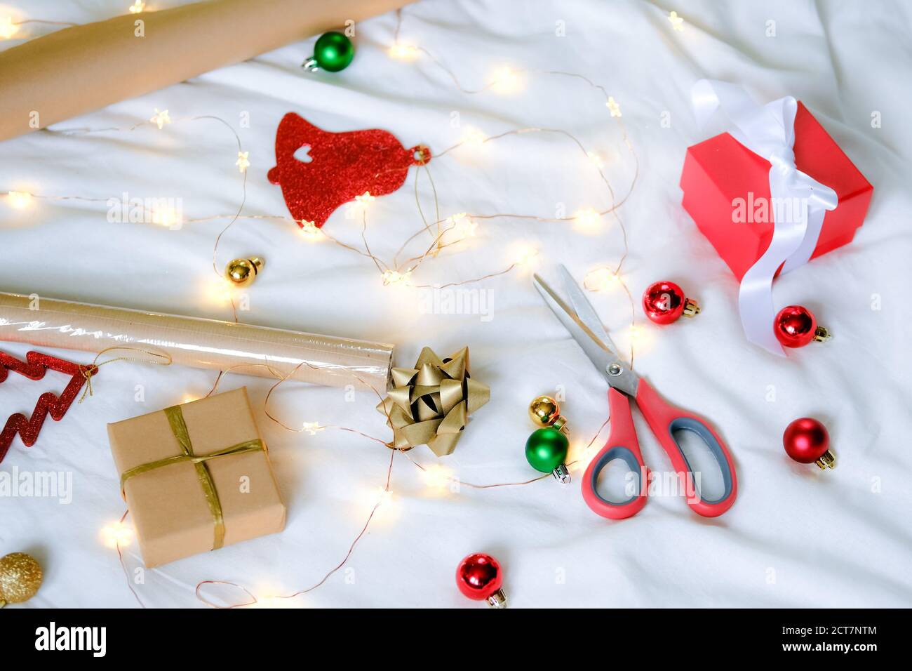 Christmas gifts wrapping, paper, scissors and accessories on white bed ...