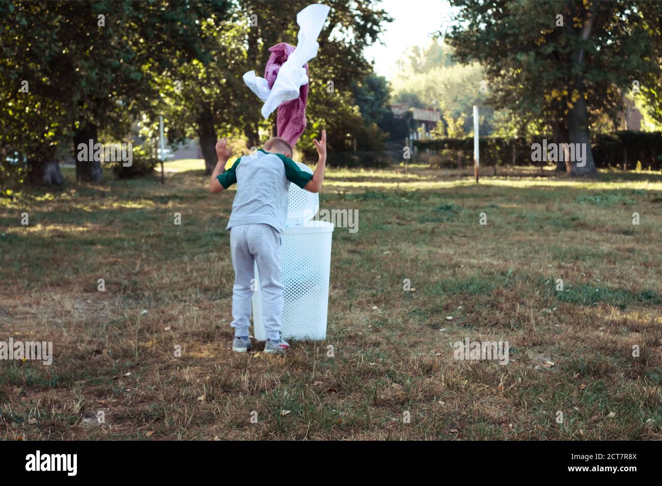 the kid throwing clothes out of the basket. outdoor Stock Photo - Alamy