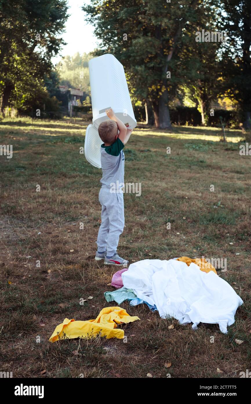 the child hiding in the laundry basket. clothes scattering on the grass ...