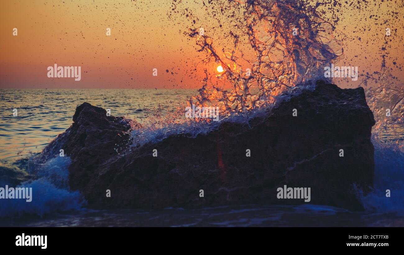 Closeup of sea waves beating against the rocks at sunset Stock Photo ...