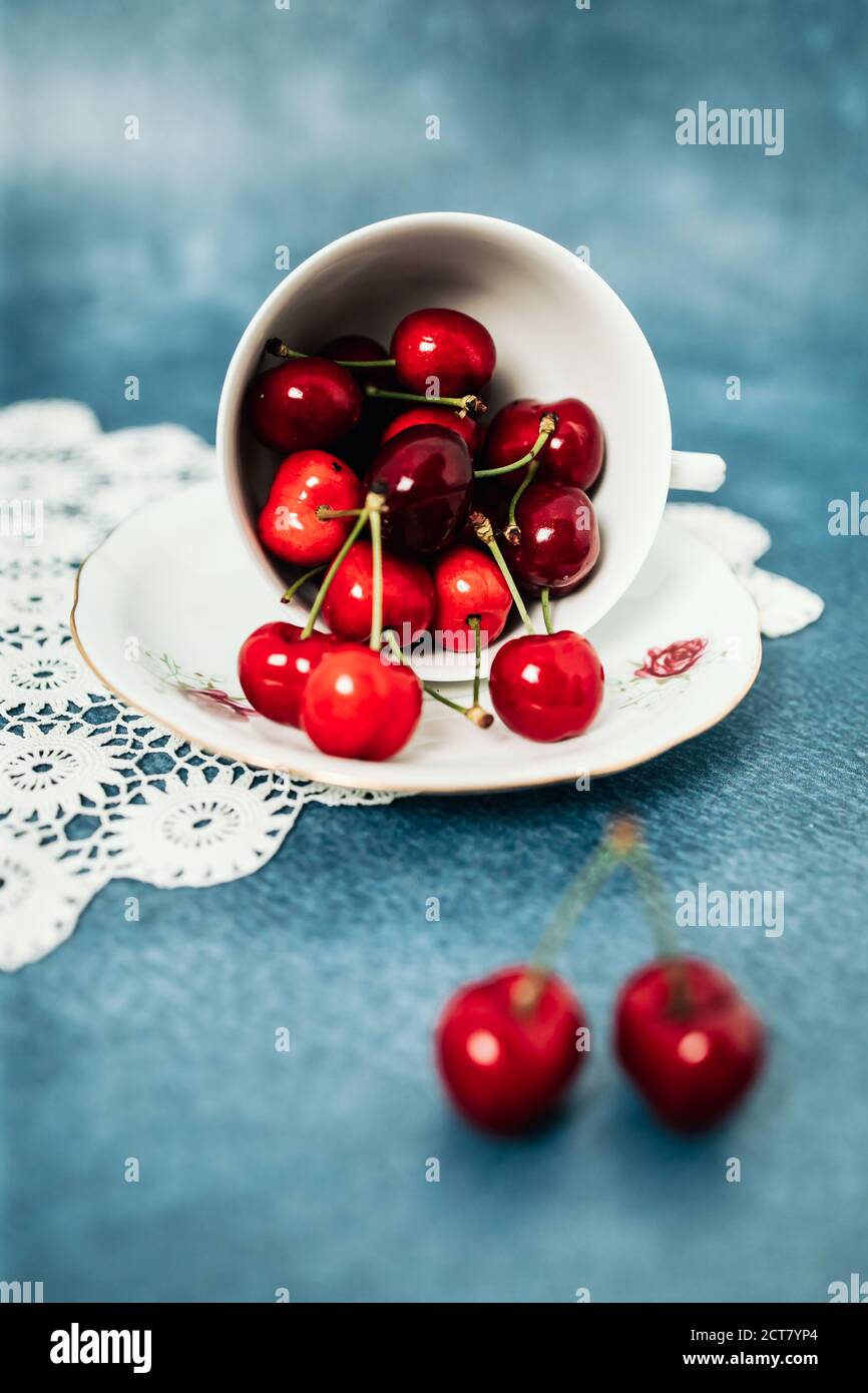 Red, delicious cherries in an old porcelain cup on the table with ...
