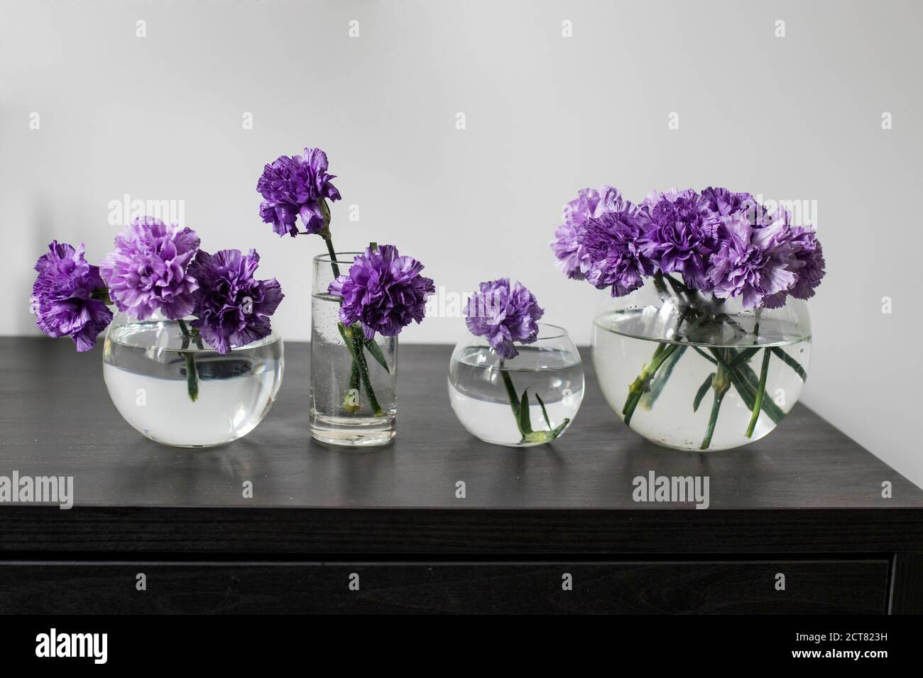 Bridal bouquets of lilac carnations in a four round glass vases ...