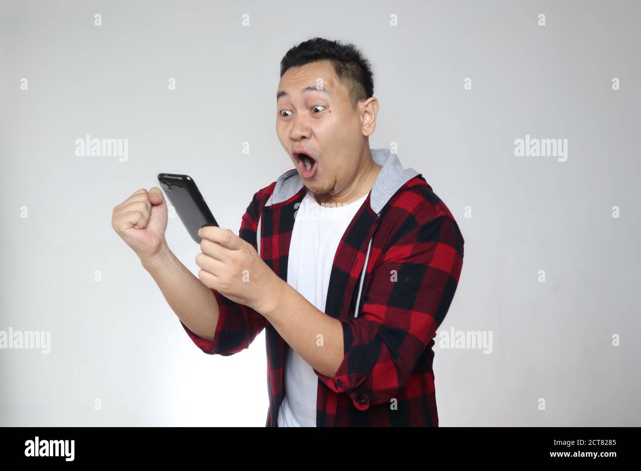 Attractive young Asian man have good news on his phone, smiling happy ...