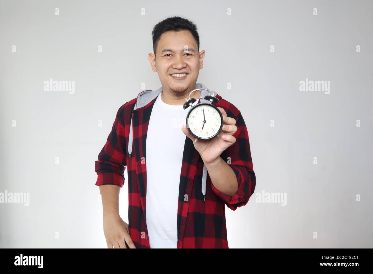 Young Asian man shows time on clock with a happy expression, time ...