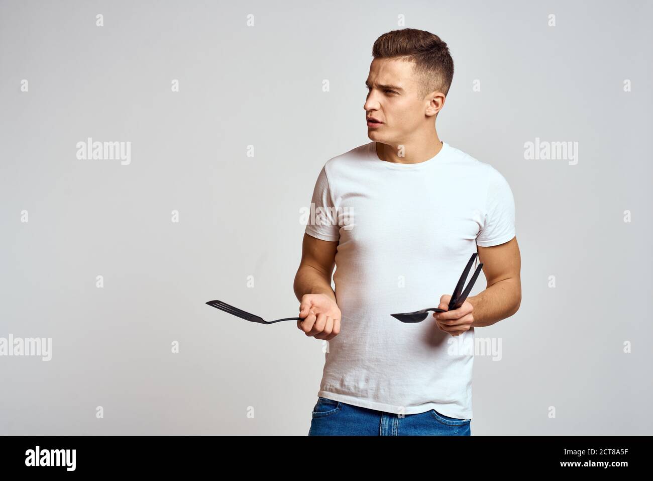 Guy with kitchen tools in hands on a light background cropped view of ...