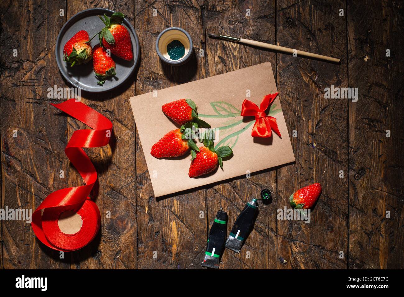 Gift card with live strawberries. On the table are satin ribbon ...
