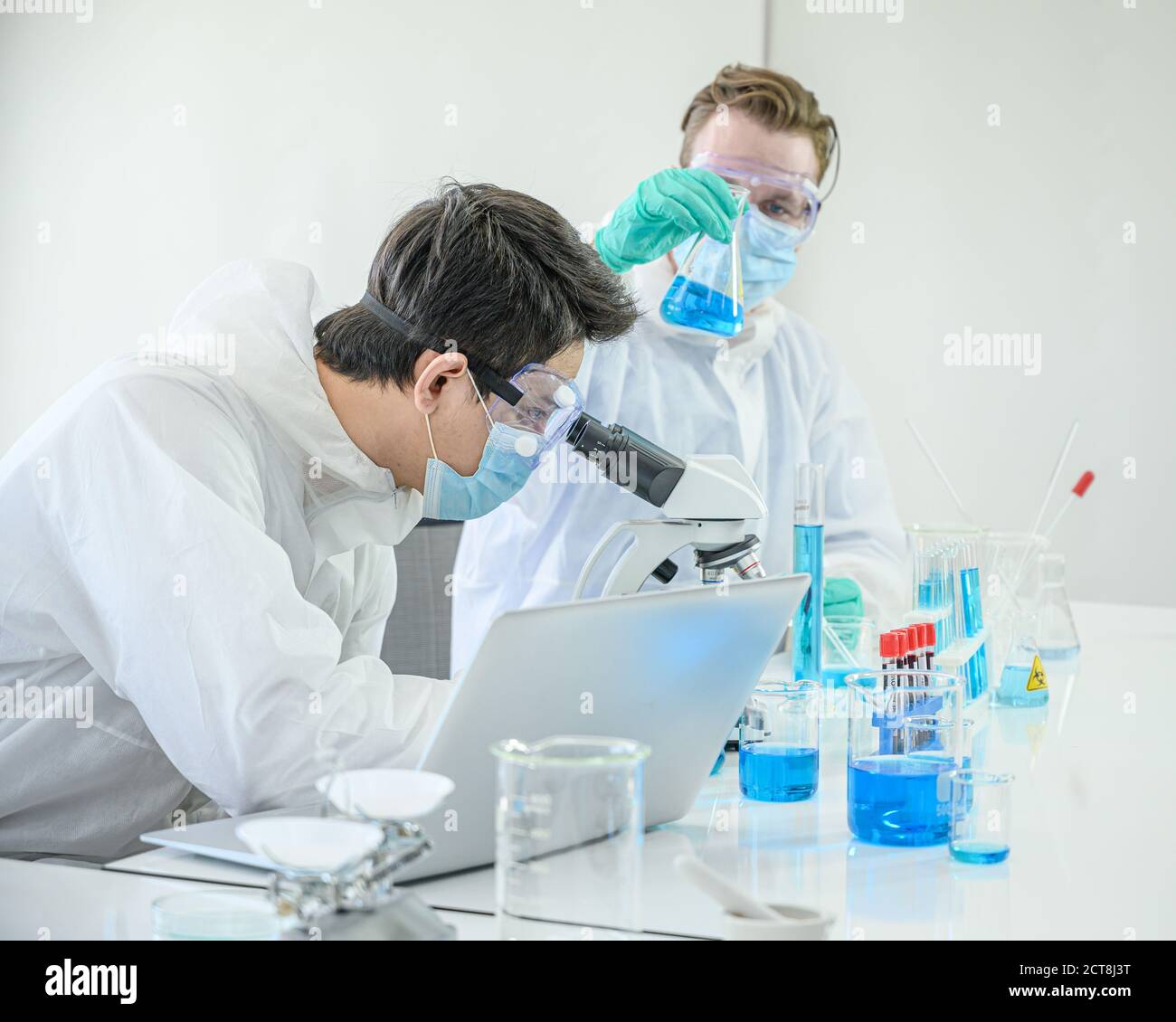 Couple male scientist wearing protection suit working with microscope ...