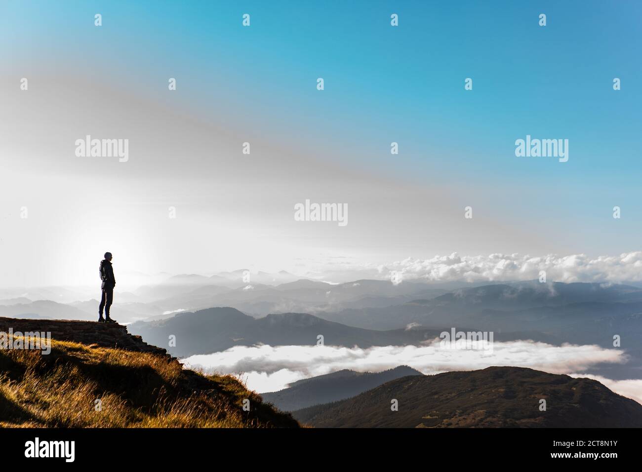man standing at the edge of the cliff looking at mountains Stock Photo ...